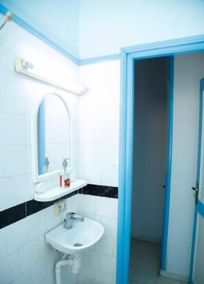 Casa de banho com lavatório branco, espelho e porta azul.