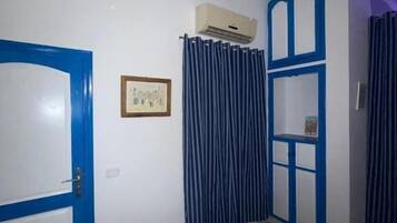 Quarto com cama, porta, aparelho de ar condicionado e cortina.
