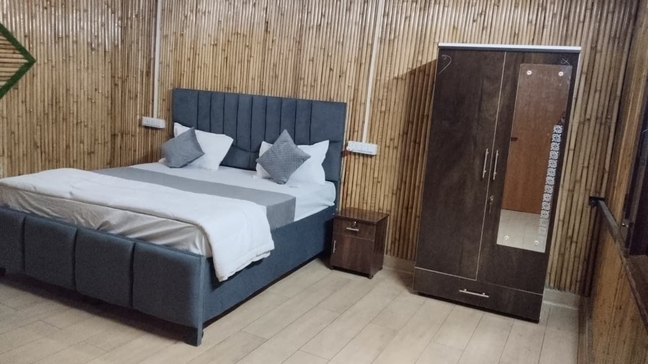 Quarto com cama, mesas de cabeceira, guarda-roupa e parede de bambu.
