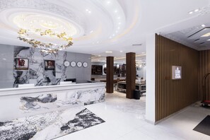 Um hall de hotel com balcão de recepção em mármore, bar no hall e design moderno no teto.