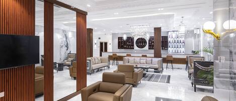 Um interior moderno com um espelho grande, sofás, um espaço de bar e uma televisão.