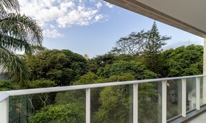 Uma varanda com vista para folhagem e árvores densas.