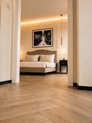 Quarto com cama, mesa de cabeceira, quadro na parede e luminária pendente.