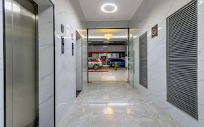 Um elevador moderno com parede de mármore e um portão fechado à direita.