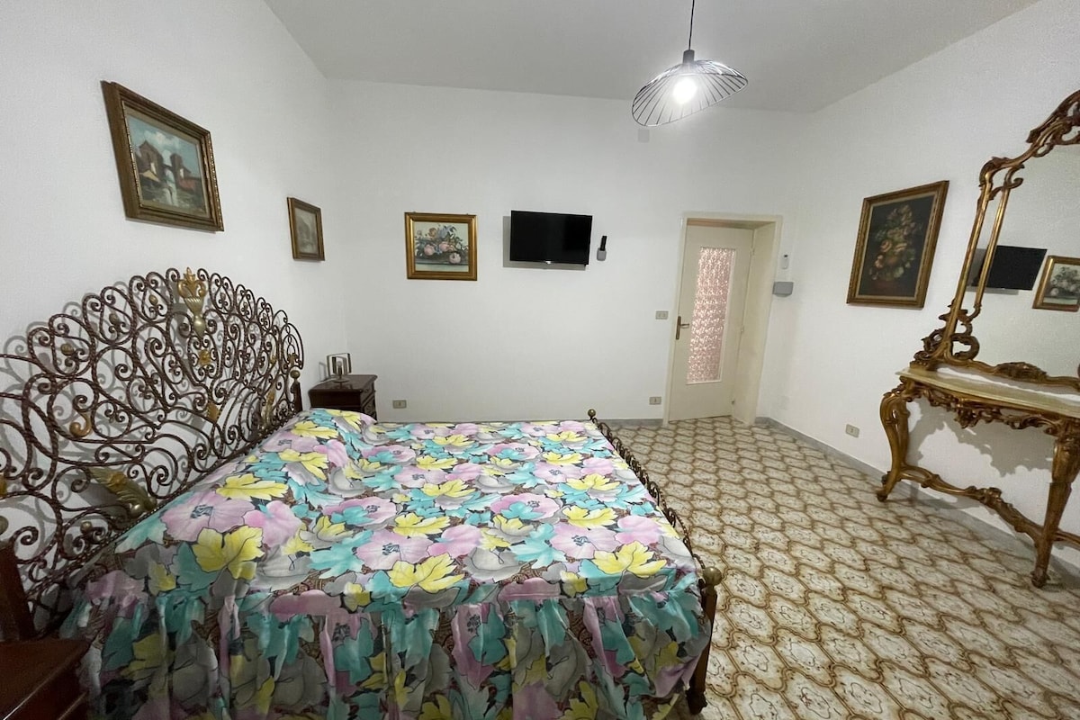 Quarto com cama, televisão, porta e espelho.