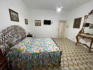 Quarto com cama, televisão, porta e espelho.