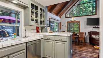 Cozinha com lava-louças, armários e área de jantar com mesa e cadeiras.