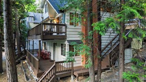 Uma casa de dois andares com varanda, escada e área de deck.
