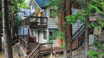 Uma casa de dois andares com varanda, escada e área de deck.