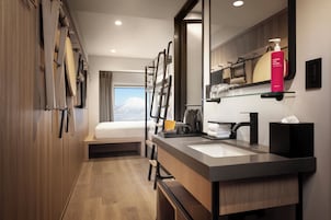 Casa de banho de hotel moderna com cama, espelho grande, pia e vista para uma montanha.