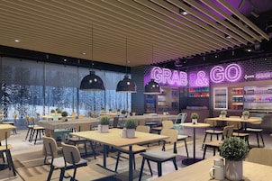Interior moderno de café com mesas, cadeiras e um letreiro de neon com a frase 'GRAB & GO'.