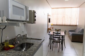 Uma cozinha compacta com micro-ondas, pia e área de refeições com mesa e cadeiras.