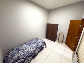 Quarto com uma cama de solteiro, um guarda-roupa e uma porta.