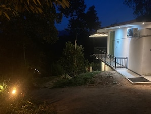 Um edifício moderno com escadaria que leva a uma entrada coberta, cercado por vegetação.