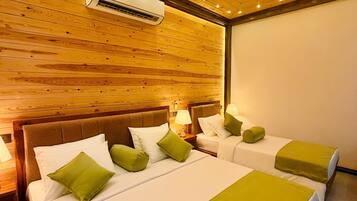 Quarto de hotel com duas camas, painéis de madeira nas paredes e um aparelho de ar condicionado.