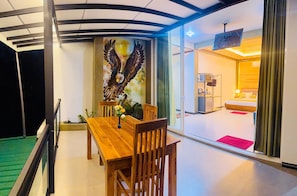 Uma área de refeições com mesa e cadeiras de madeira, um vaso com flores e um grande mural na parede com a imagem de uma águia.