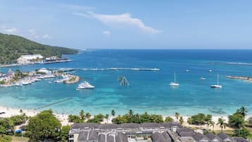 Uma área costeira com um porto de iates, barcos e uma praia.