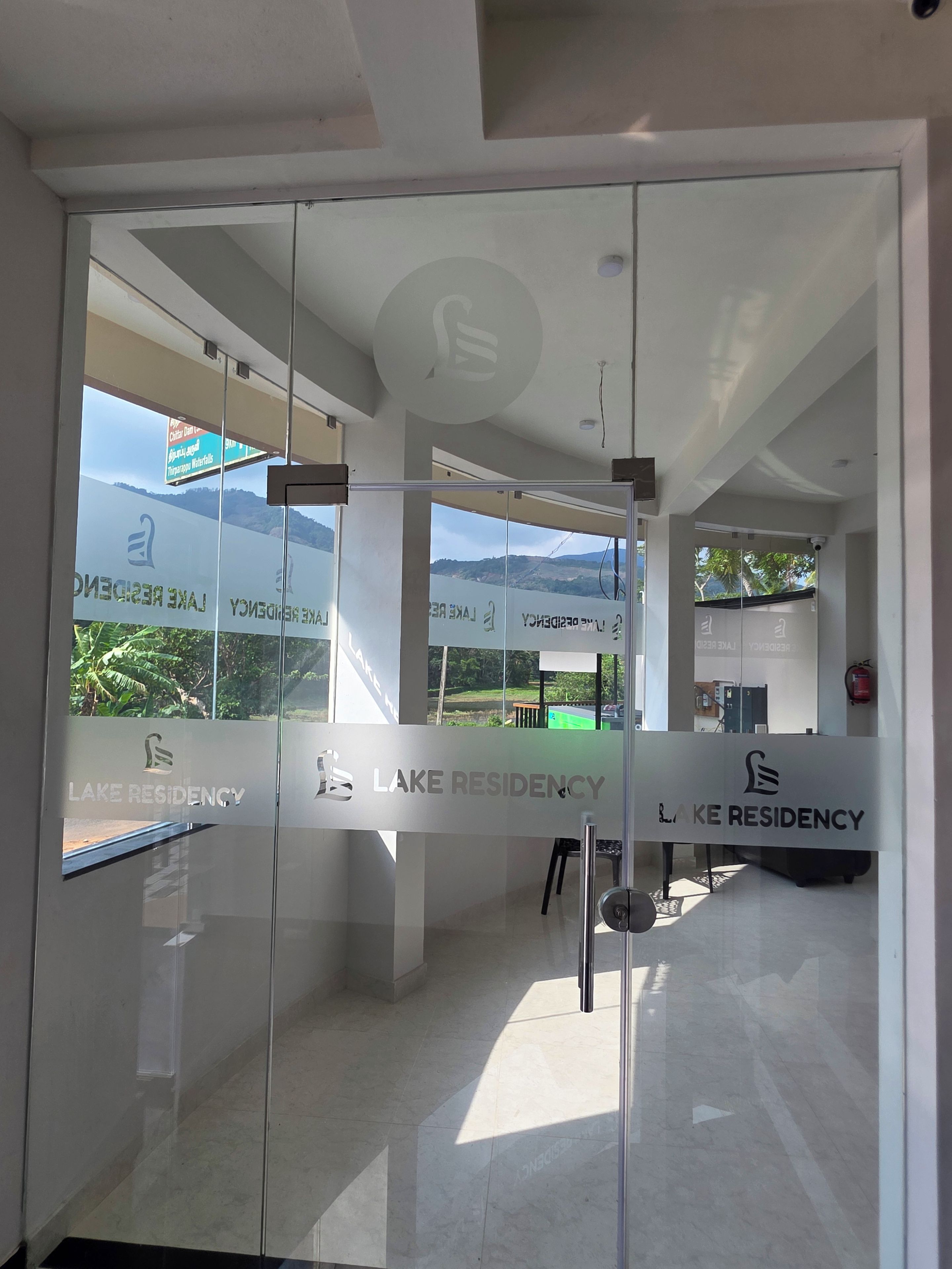Interior moderno com portas de vidro, balcão de recepção e vista para uma paisagem montanhosa.