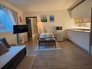 Apartamento moderno com área de refeições, cozinha compacta e televisão de tela plana.
