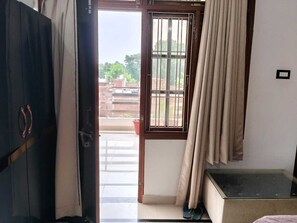 Quarto com porta de correr para uma varanda, cama com cabeceira de vidro e guarda-roupa.