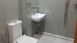 Casa de banho com sanita, lavatório e chuveiro.
