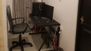 Quarto com escrivaninha, duas cadeiras, computador e porta.