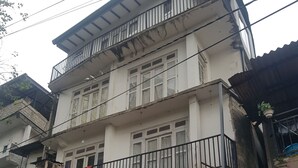 Edifício de vários andares com sacadas, um portão verde e uma motocicleta estacionada.