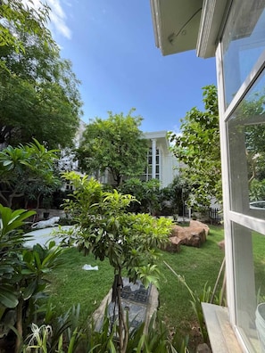 Jardim bem cuidado com diversas plantas e um pequeno lago.