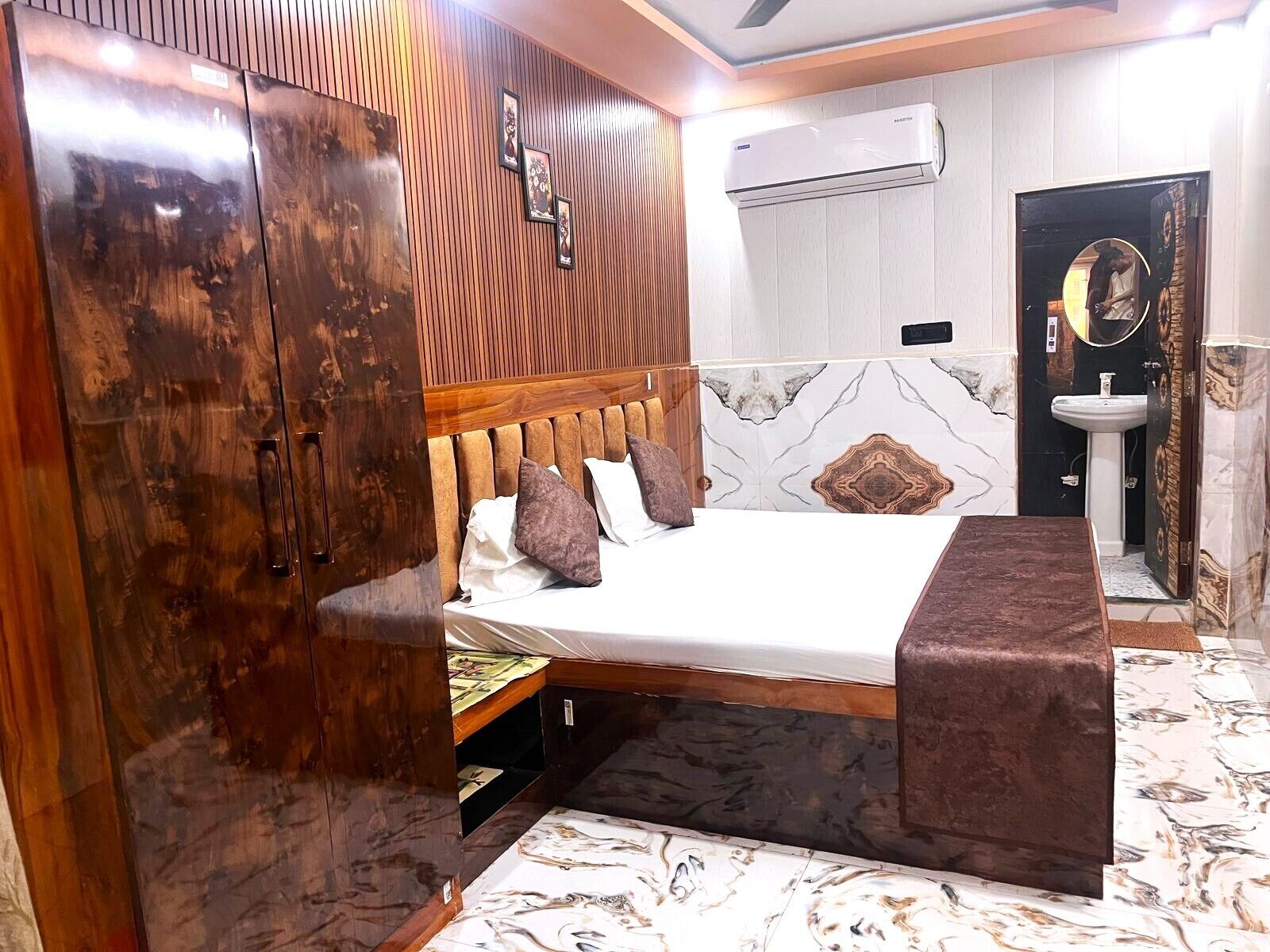 Quarto com cama, guarda-roupa de madeira e banheiro com pia e espelho.