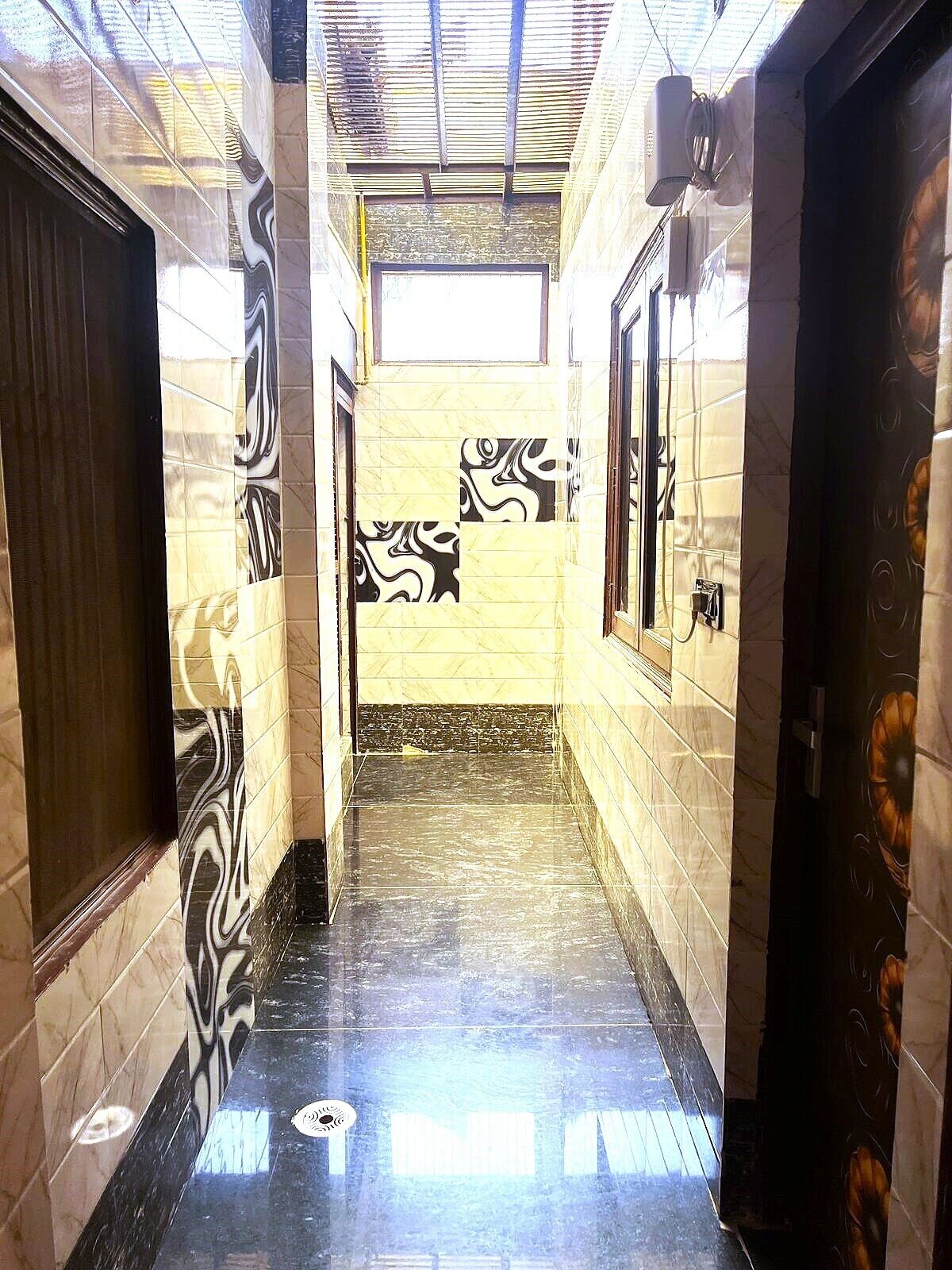 Um corredor com paredes estampadas e piso brilhante, que leva a uma porta com design floral.