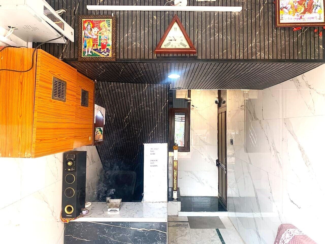 Um saguão de hotel com balcão de recepção em madeira, um relógio e uma parede de mármore.