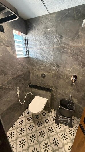 Casa de banho com sanita, chuveiro e lavatório.
