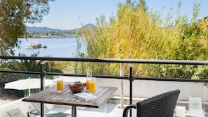 Mesa com vista para um lago, rodeada por vegetação e céu claro.