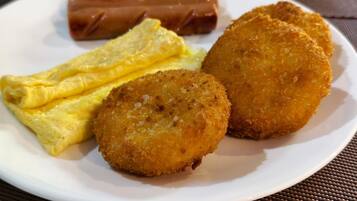 Um prato com dois alimentos fritos, um omelete dobrado e uma salsicha.