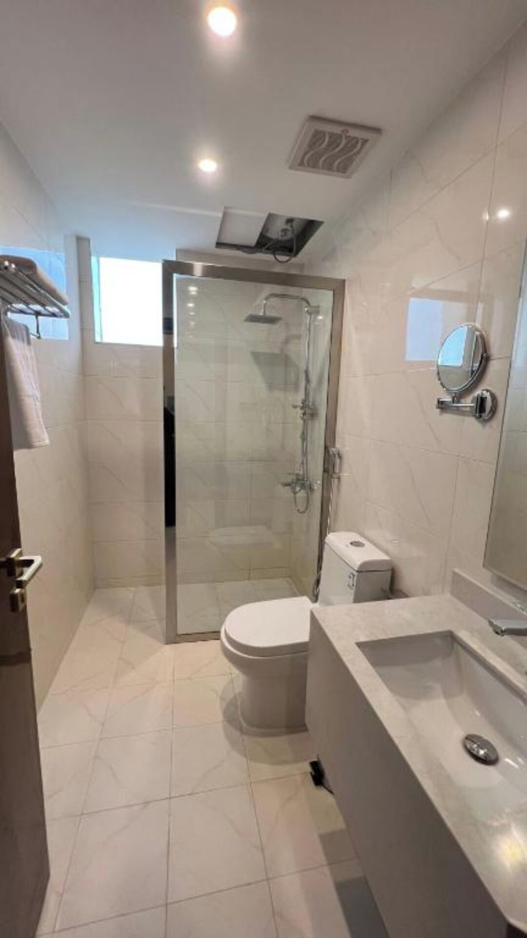 Casa de banho moderna com cabine de duche em vidro, sanita e lavatório com espelho.