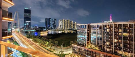 Paisagem urbana noturna com edifícios modernos, uma ponte e um rio.