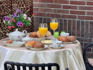 Mesa de café da manhã com croissants, ovos e copos de suco.