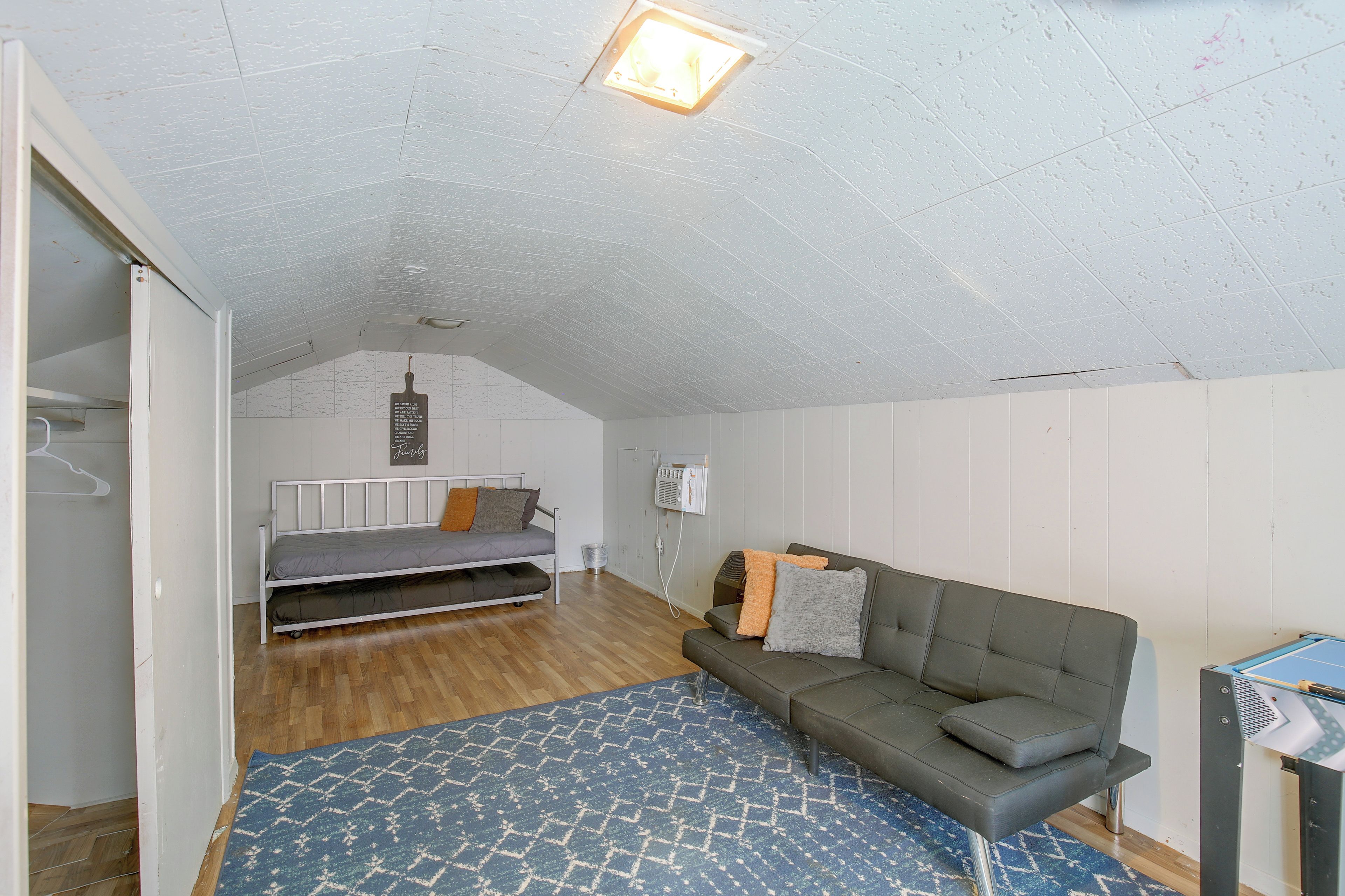 Quarto compacto com cama beliche, sofá e tapete estampado.