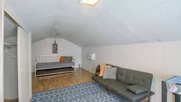 Quarto compacto com cama beliche, sofá e tapete estampado.