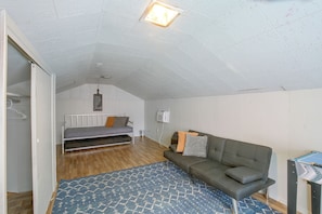 Quarto compacto com cama beliche, sofá e tapete estampado.