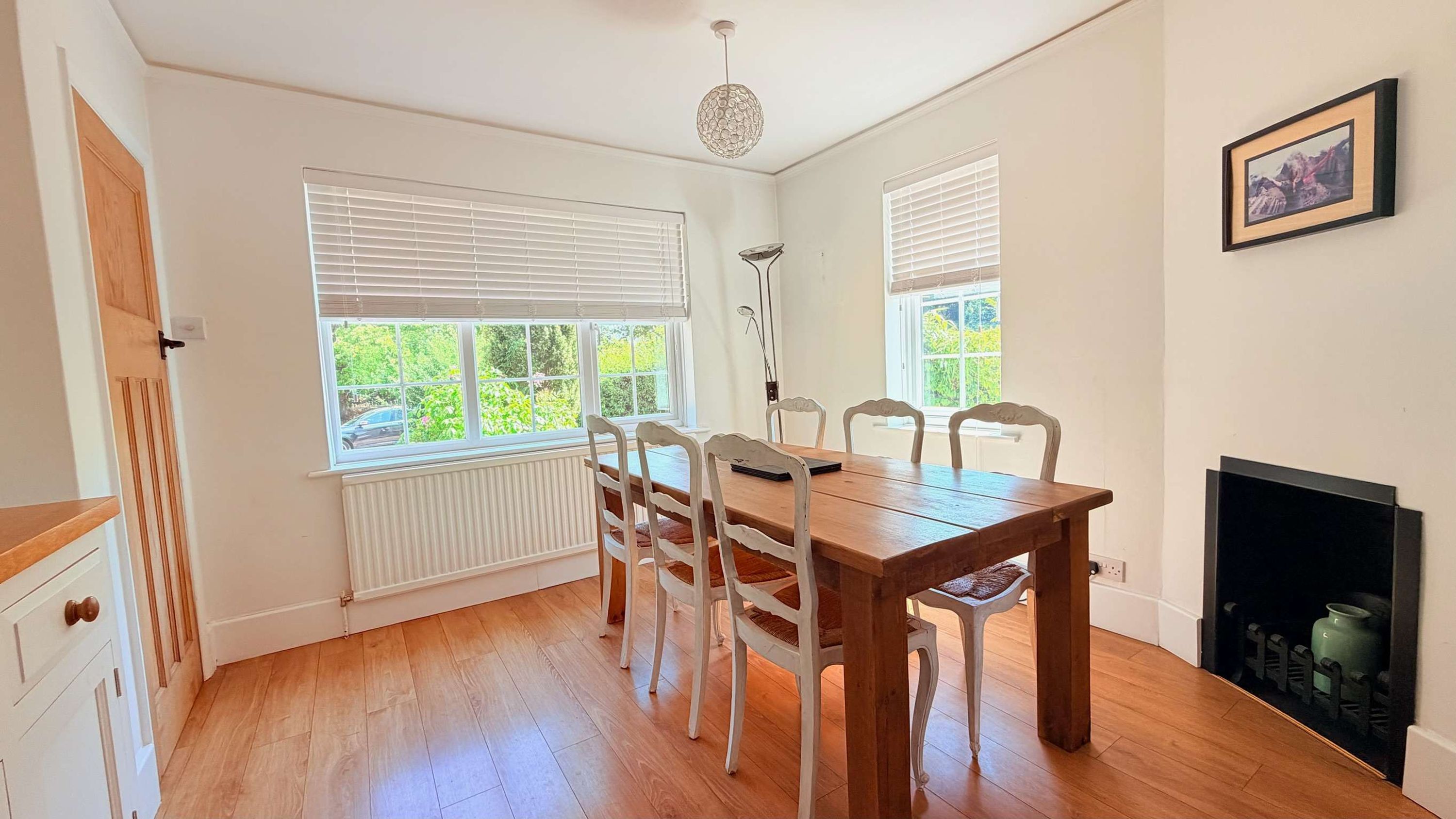 Uma sala de jantar com mesa e cadeiras de madeira, um radiador e uma lareira.