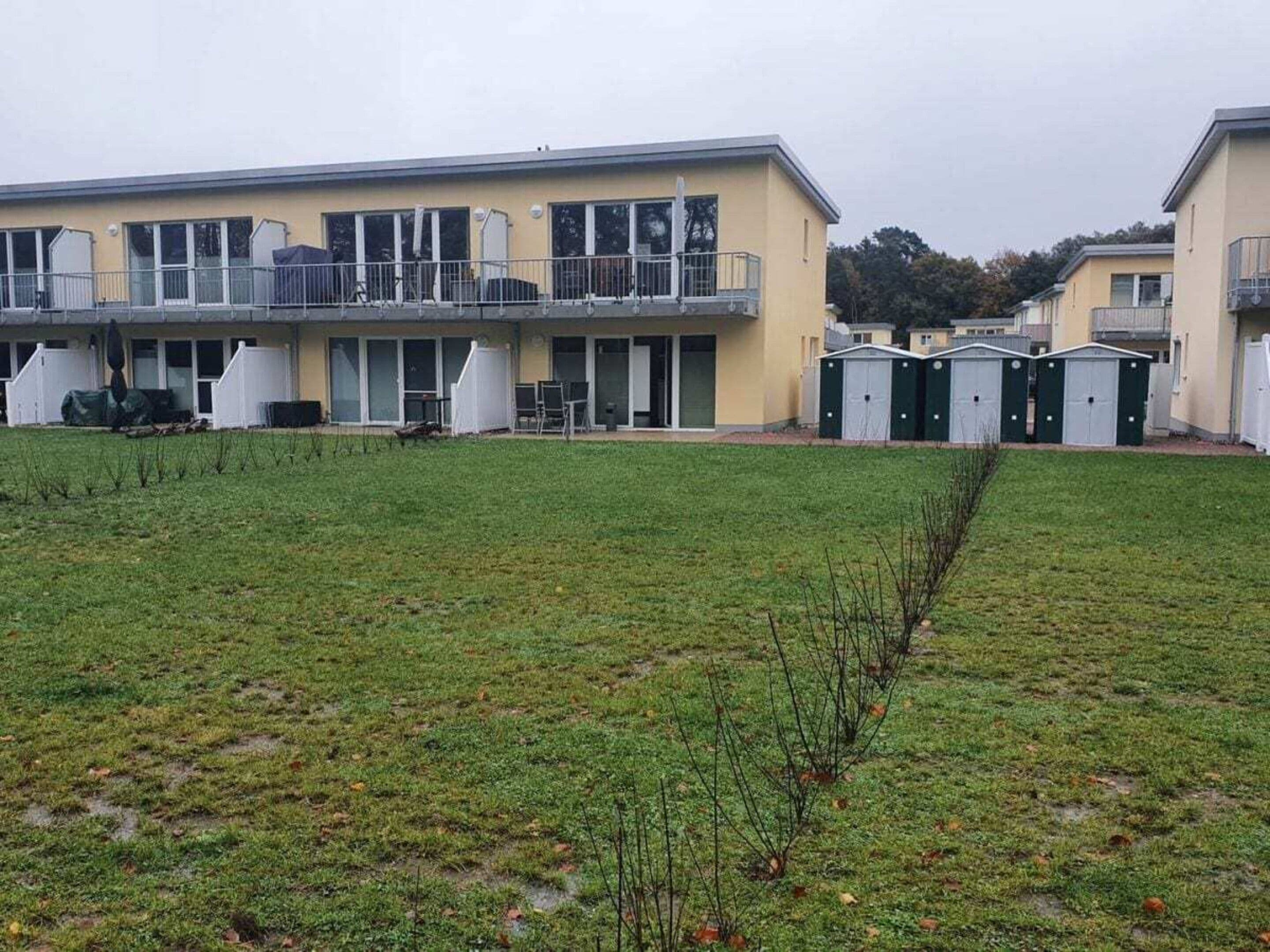 Um edifício com telhado plano, janelas amplas e área externa coberta com cadeiras.
