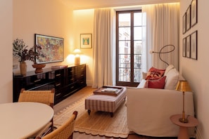 Uma sala de estar aconchegante com sofá, mesa de centro, mesa de jantar e estante de livros.