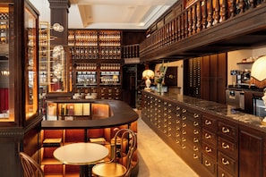 Espaço de bar com balcão curvo, assentos e display de vinhos.