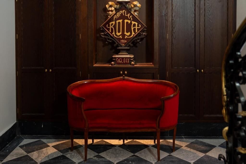 Quarto com sofá vermelho, armário de madeira e uma placa fixada na parede.