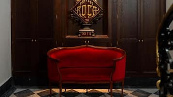 Quarto com sofá vermelho, armário de madeira e uma placa fixada na parede.