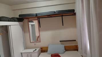Quarto pequeno e compacto com beliche, mesa de cabeceira, espelho e guarda-roupa.
