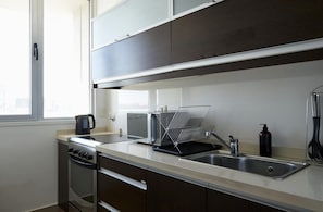 Cozinha moderna equipada com forno embutido, micro-ondas, chaleira e pia.
