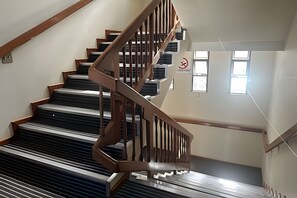 Escada com guarda-corpo e corrimão de madeira, levando a um andar superior.
