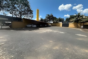 Um estacionamento ao ar livre com um edifício amarelo e uma construção alta ao fundo.